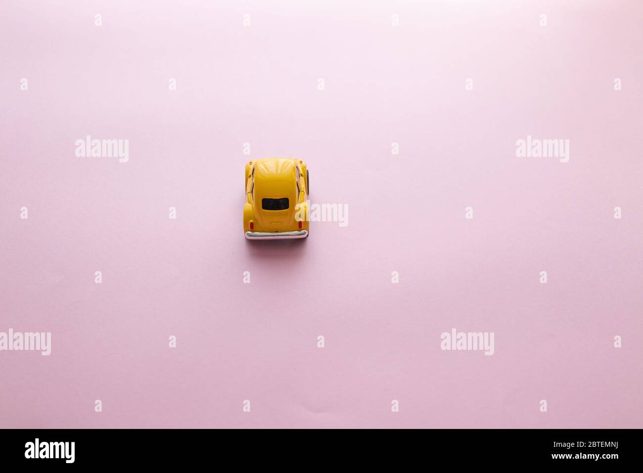 Minimal concept of a small yellow toy car on a beautiful surface, rear ...