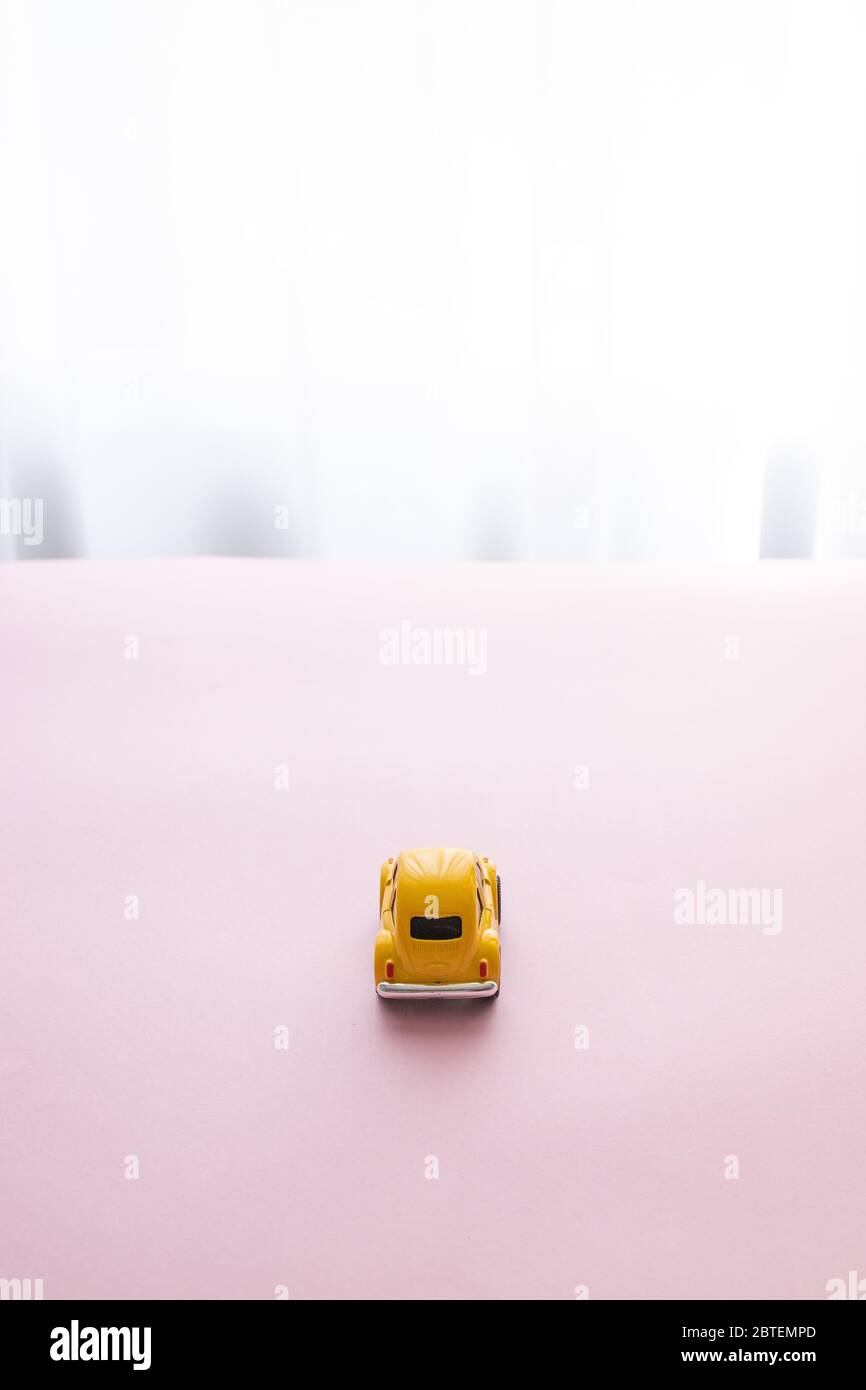 Minimal concept of small yellow toy car on a beautiful surface, rear ...