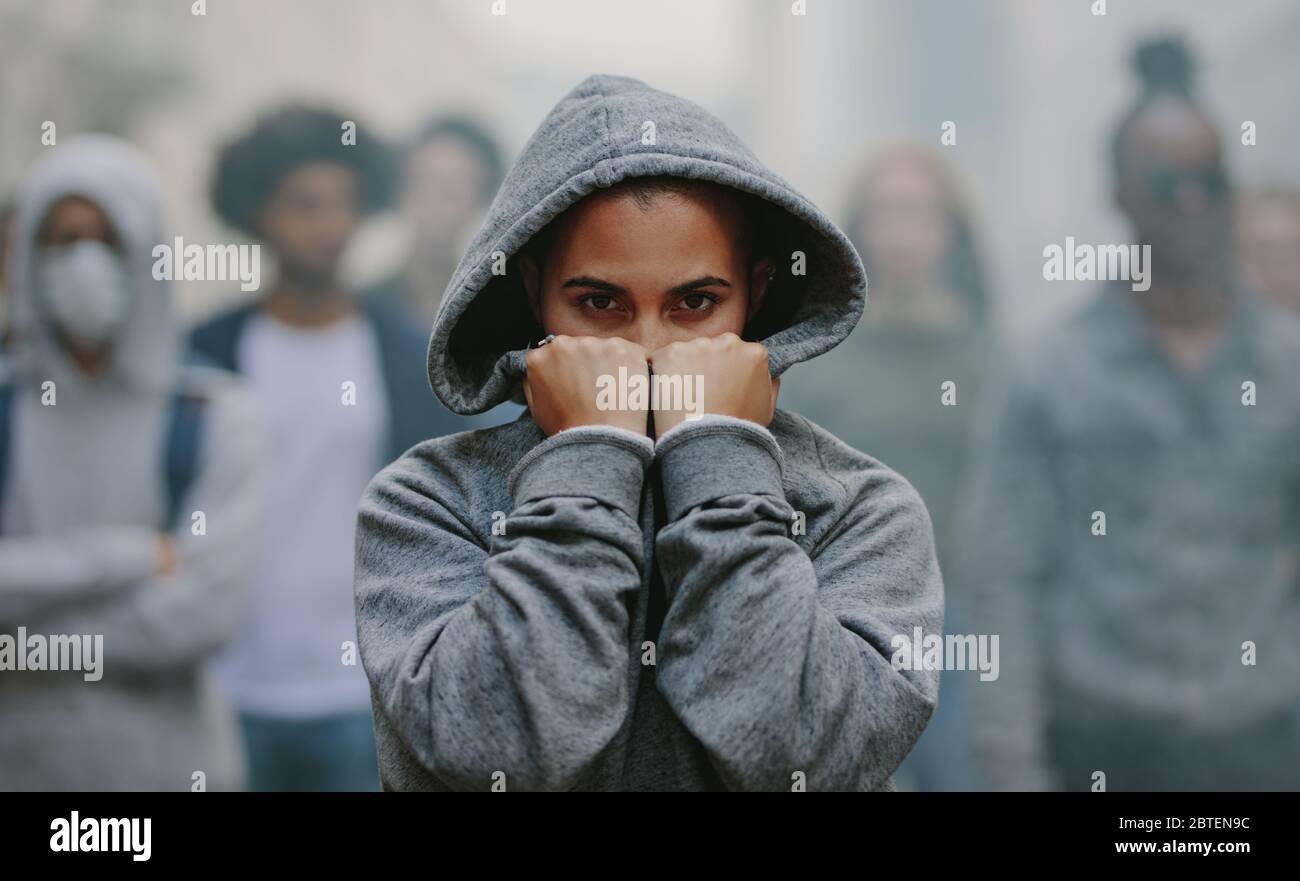 Woman activist in hooded shirt covering her face with her hands doing ...
