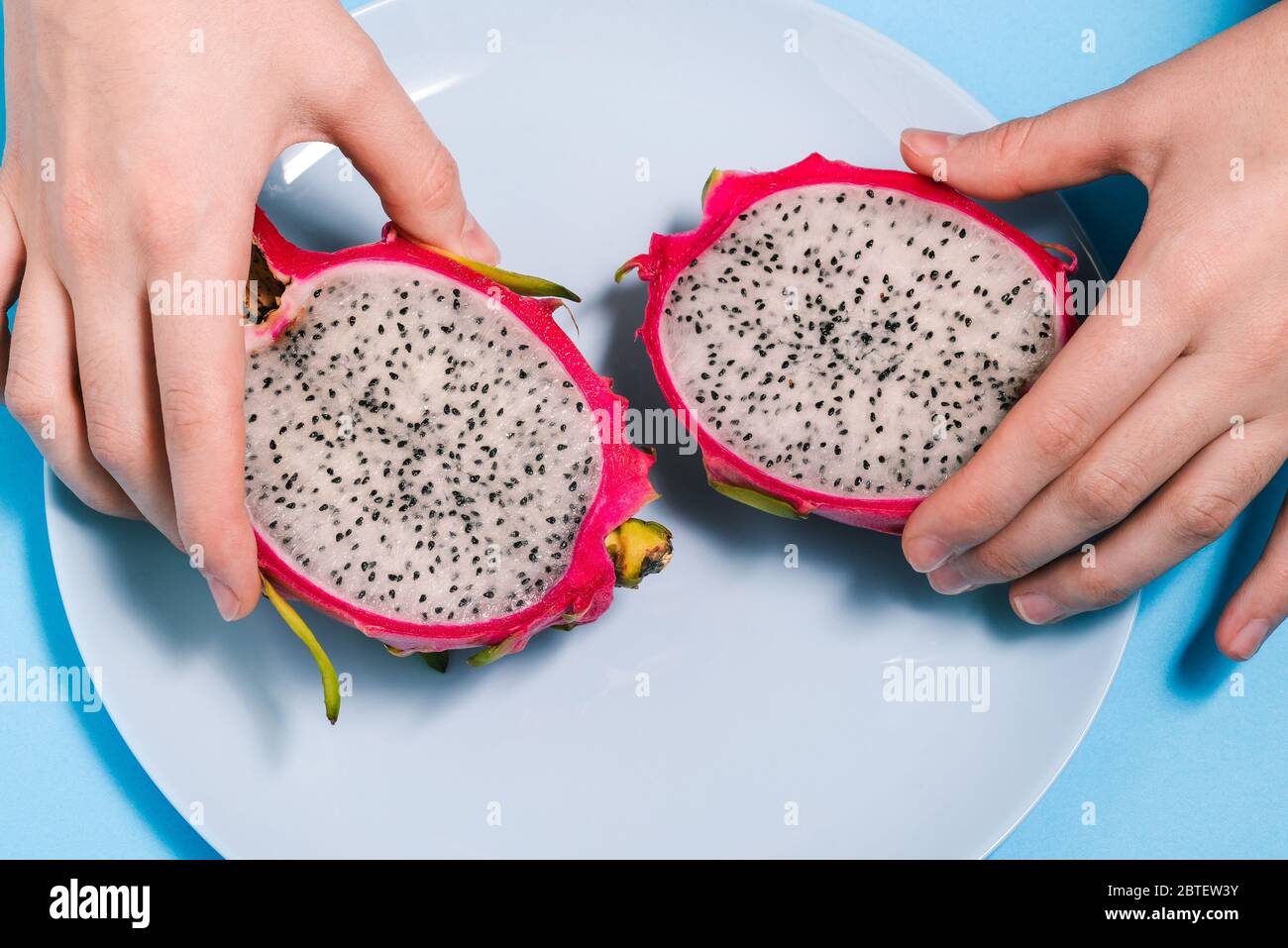 Pitaya cut into two halves close-up. A man's hands hold a ripe dragon ...