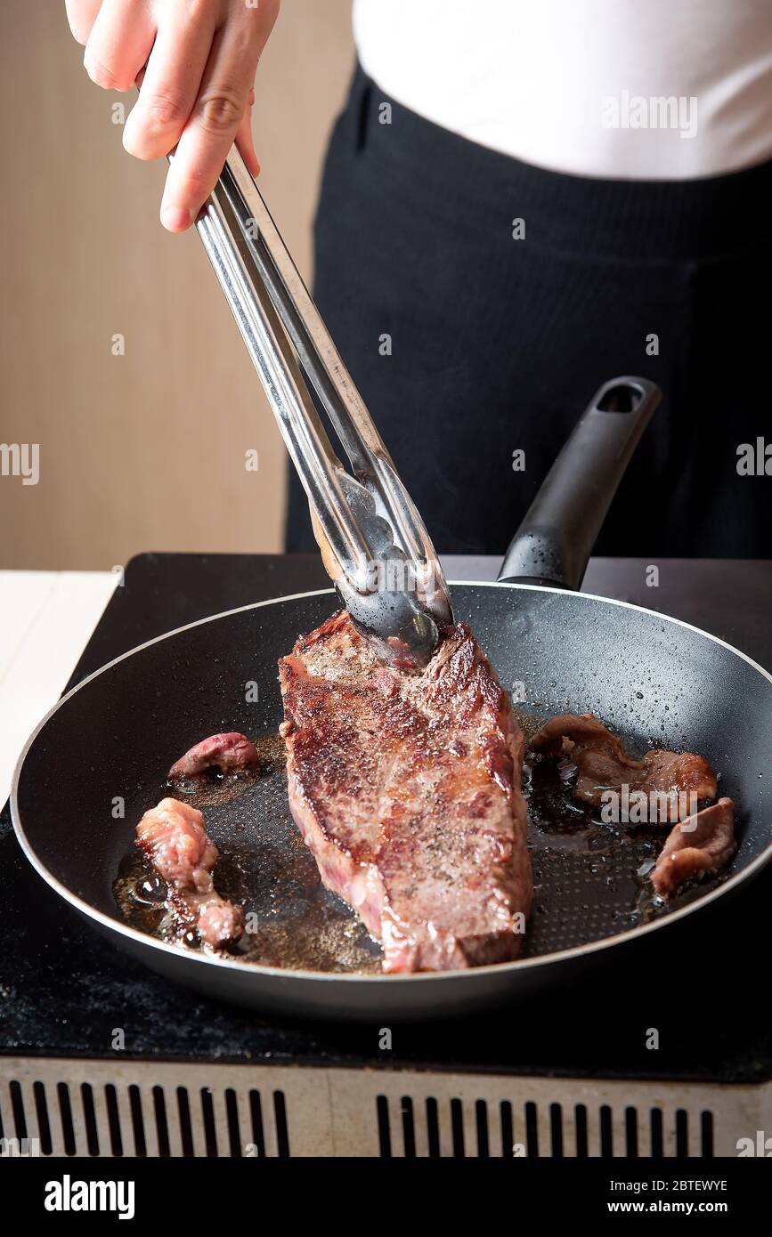 Woman frying beef steak frying on the pan. Home food preparation Stock ...