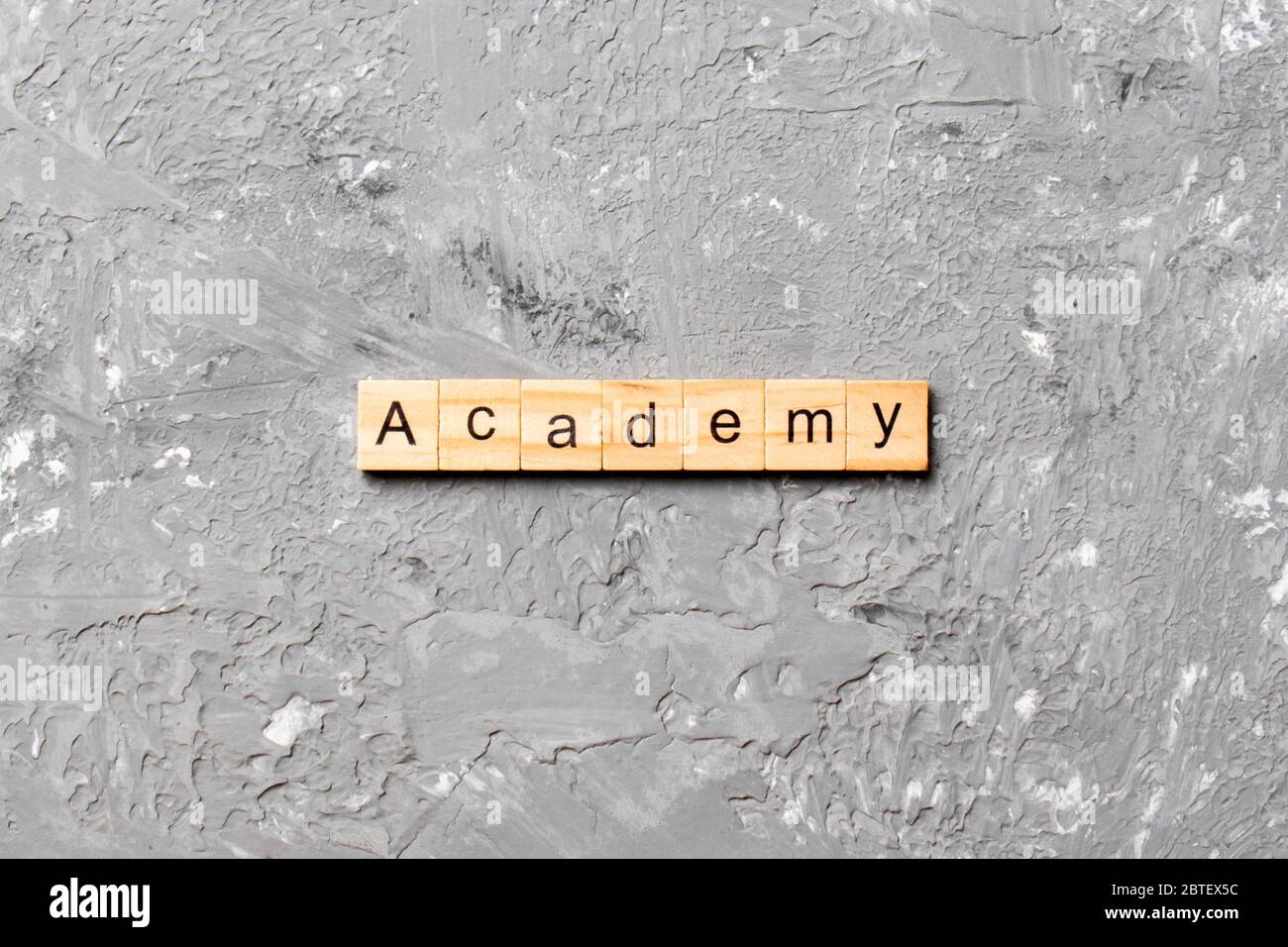 ACADEMY word written on wood block. ACADEMY text on cement table for ...