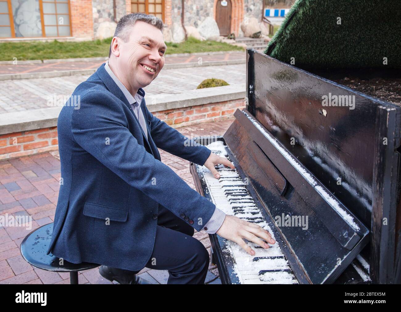 man playing the piano outdoor on early spring cold snowy day Stock ...