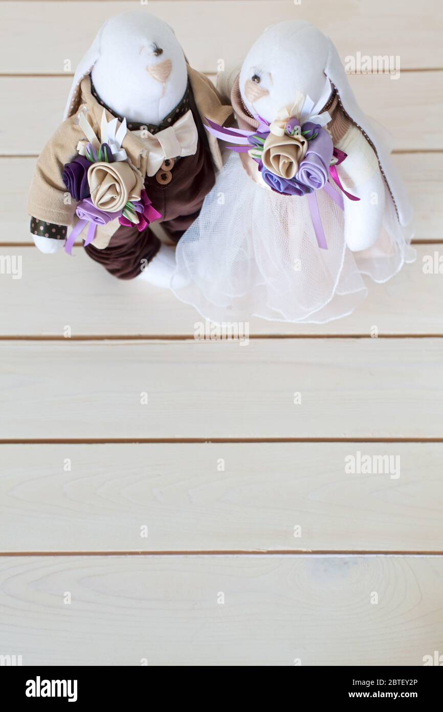 Two handmade rabbits hold a basket with eggs. White wood background ...