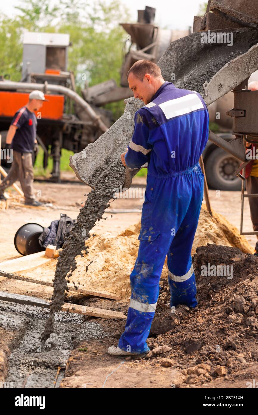 Construction worker laying cement or concrete into the foundation ...