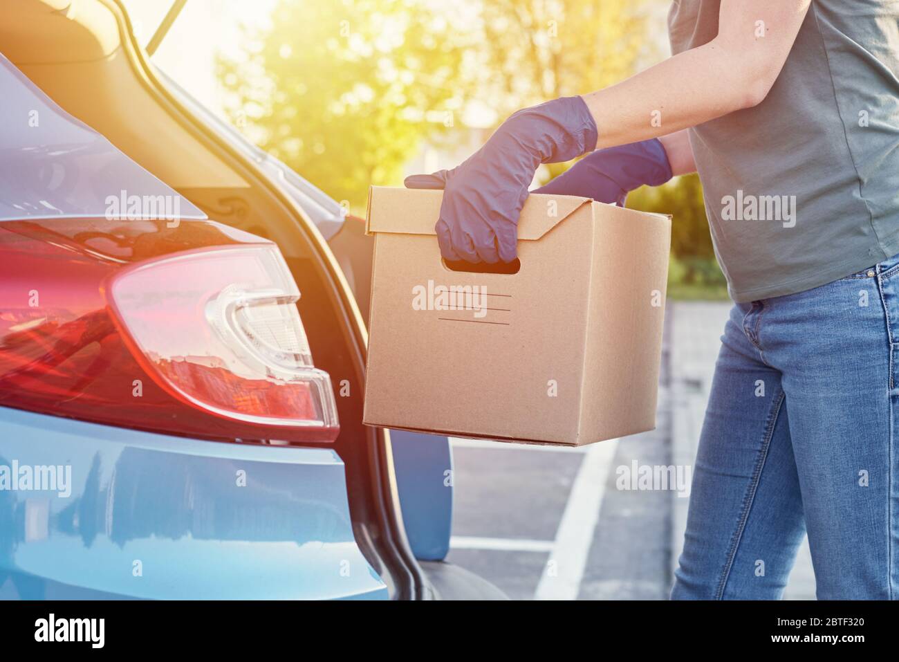 Delivery and volunteering concept. Woman in gloves load box in car ...
