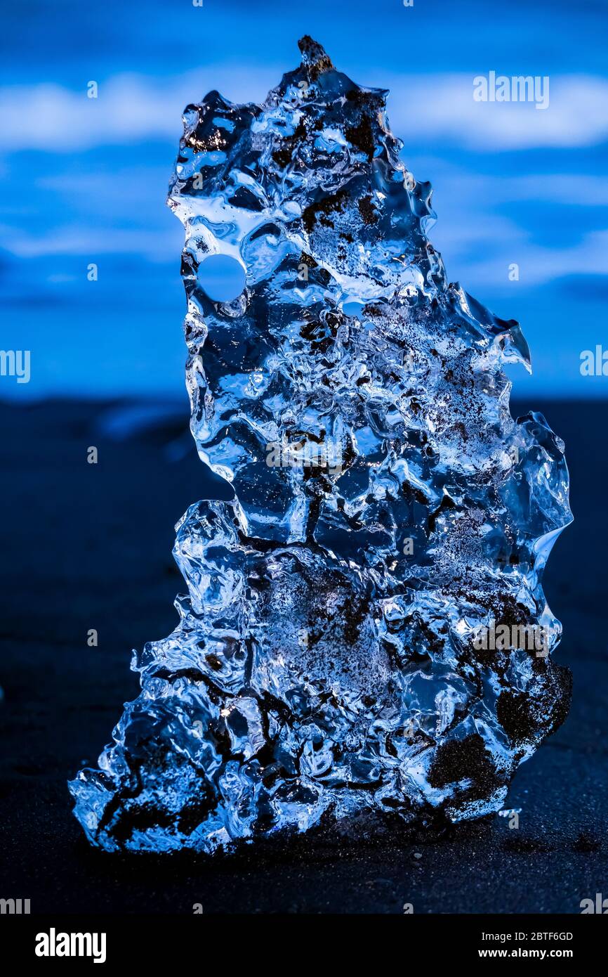Melting chunk of clear glacial ice, originally calved into Jökulsárlón ...