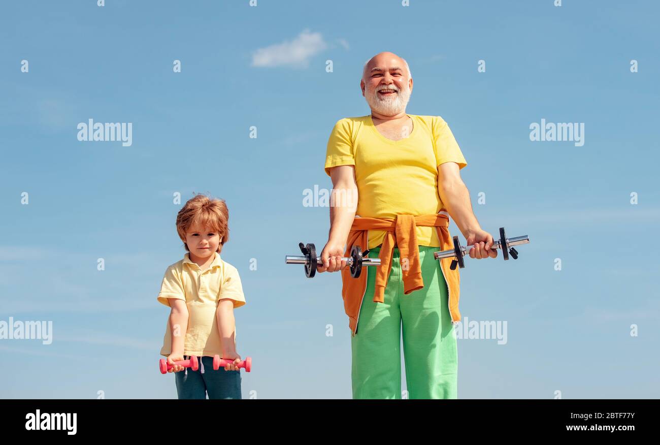 Portrait of a healthy father and son working out with dumbbells over ...