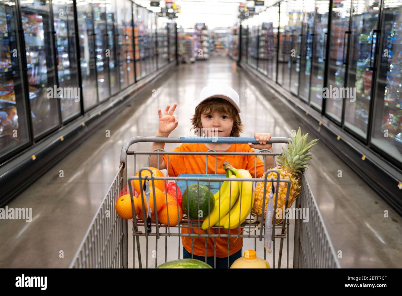 Joyful child boy in supermarket buys vegetables. Healthy food for ...