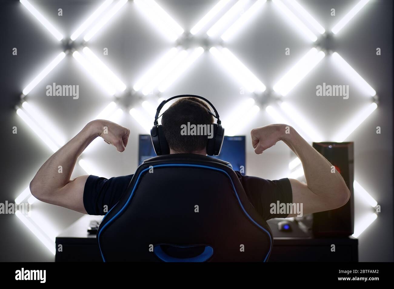 Back view of young gamer guy in headphones screaming and rejoicing ...