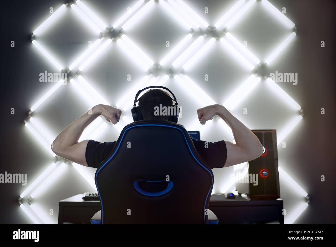 Back view of young gamer guy in headphones screaming and rejoicing ...