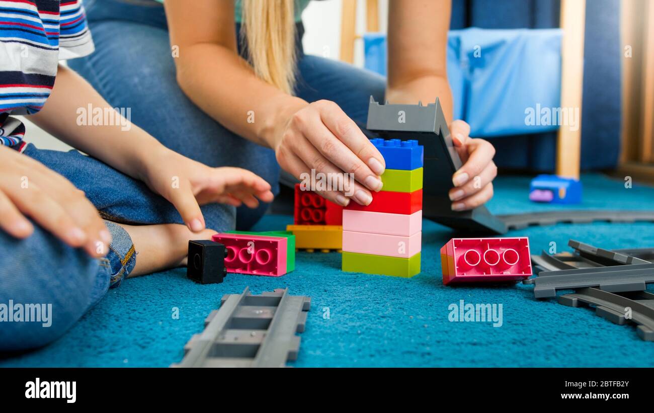 Closeup image of mother and son assembling toy bridge from colorful ...