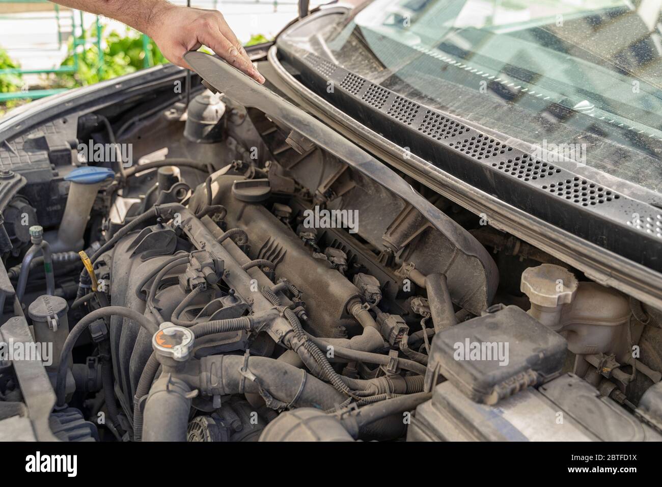 Auto mechanic works in the garage. Repair. Removing engine cover for ...