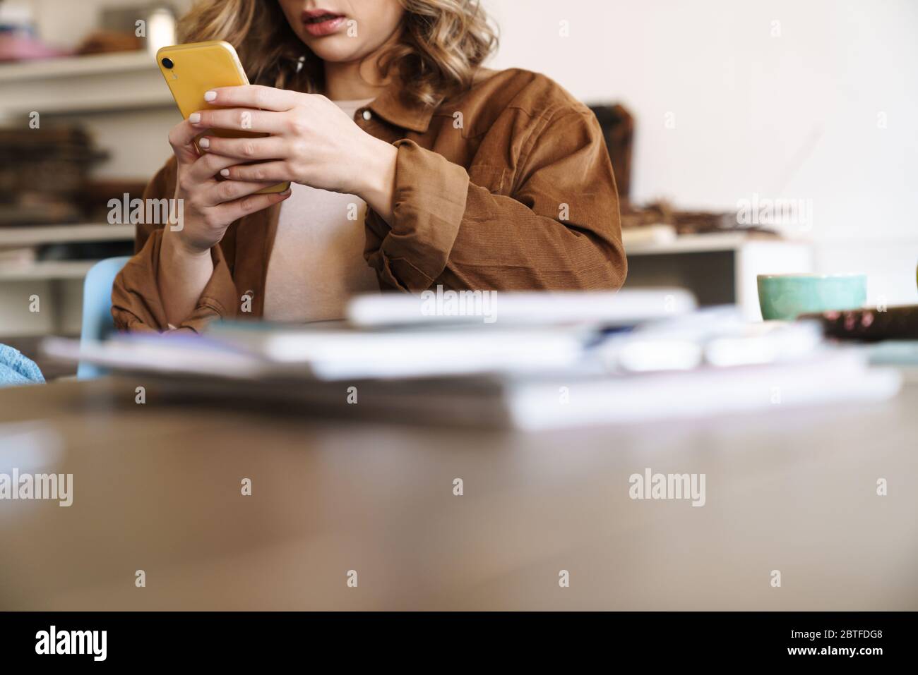 Cropped image of serious woman using cellphone while studying with ...