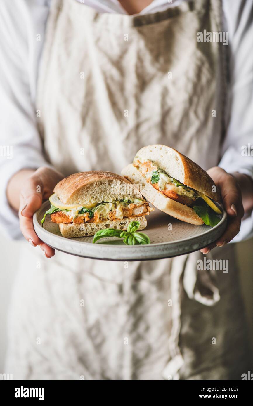 Woman holding plate with fresh fried fish sandwich with lemon Stock ...