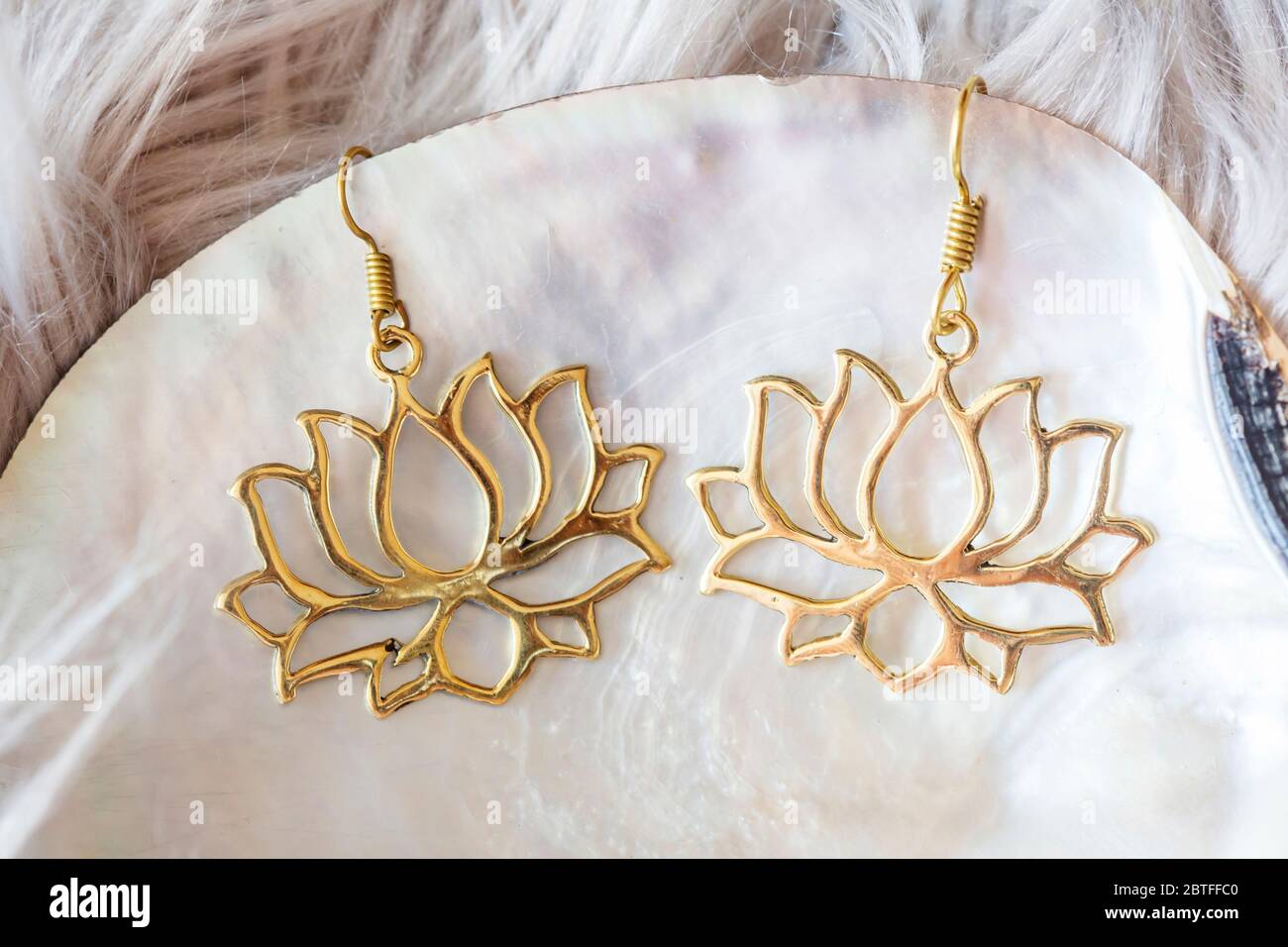 Metal earrings in lotus shape on white pearl shell background Stock ...