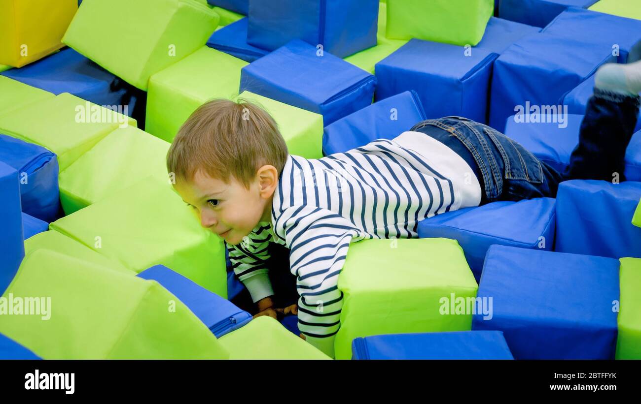 Portrait of active little boy having fun and playing in soft pit at ...
