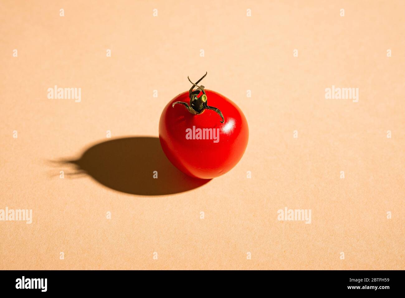 Single cherry tomato vegetable, fresh ripe food on minimal cream ...