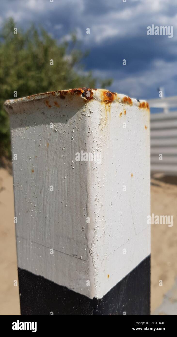 Closeup of old rusty metal pillar painted in white and black colors ...