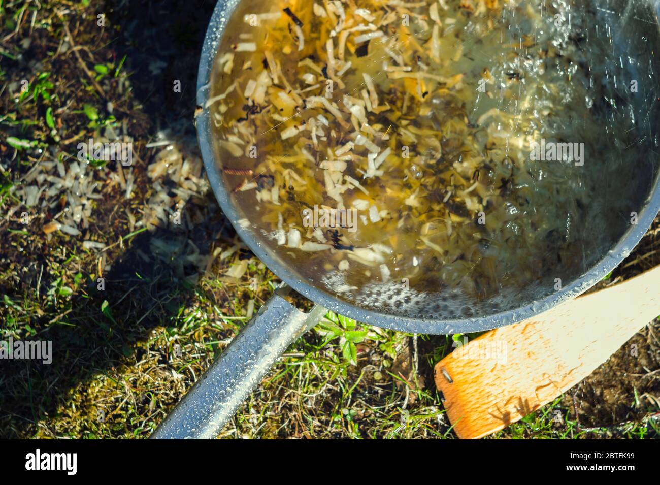 Washing dirty greasy stainless frying pan under water, outdoor cropped ...