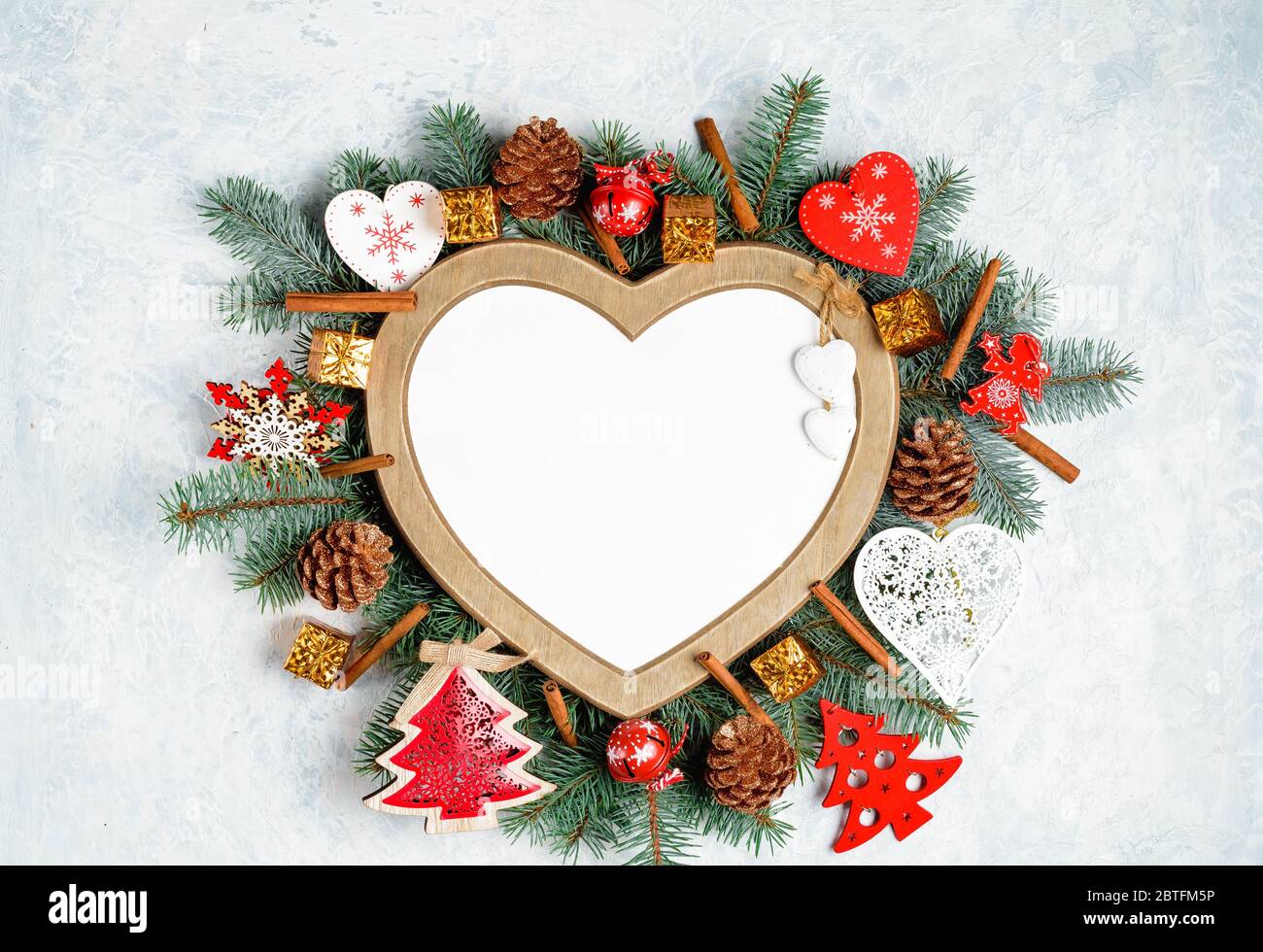 Christmas frame in the shape of a heart is surrounded by branches of a ...