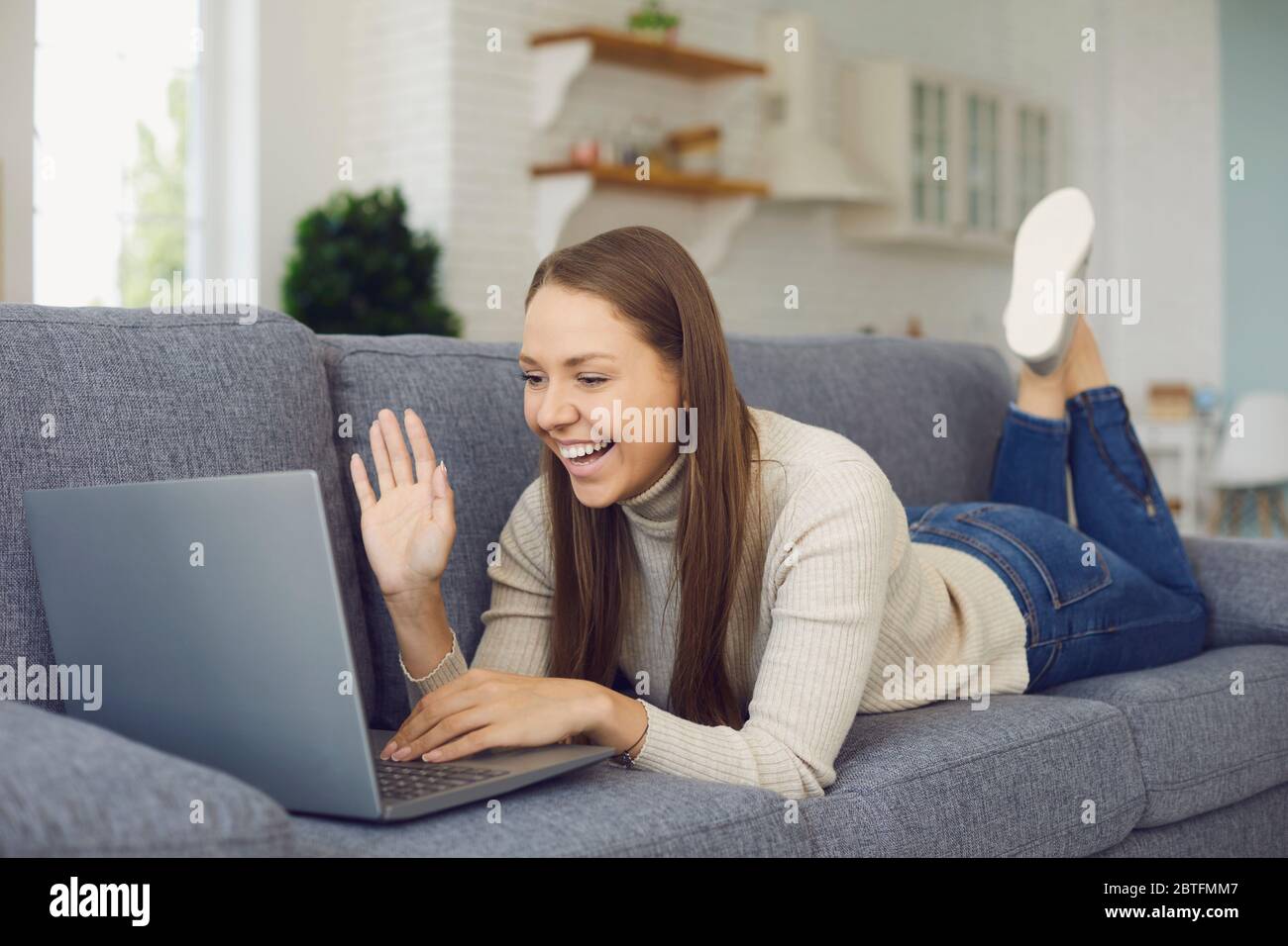 Girl blonde smiles looking uses laptop chat call application in casual ...