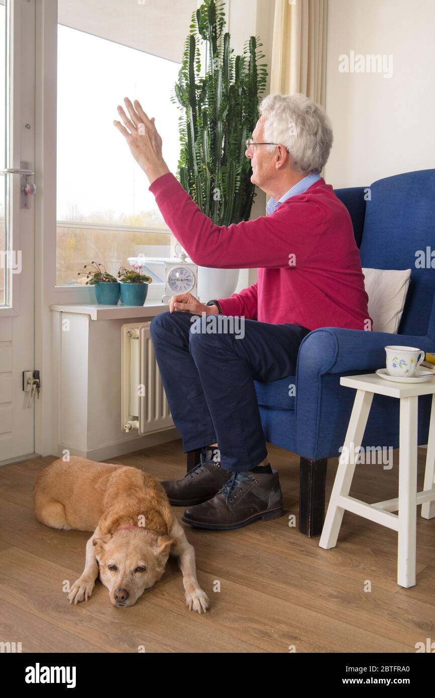 Senior man alone sitting in chair and looking outside Stock Photo - Alamy