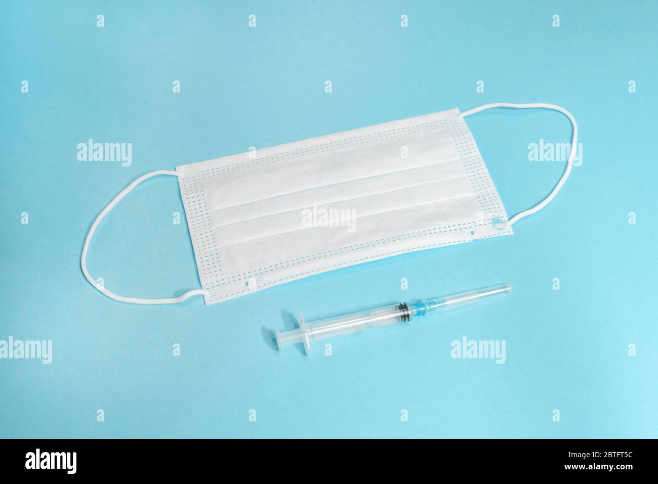 A white medical protection mask with syringe on the blue background ...