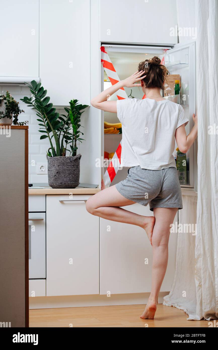 Woman standing on one leg in front of the frige sealed with barrier ...