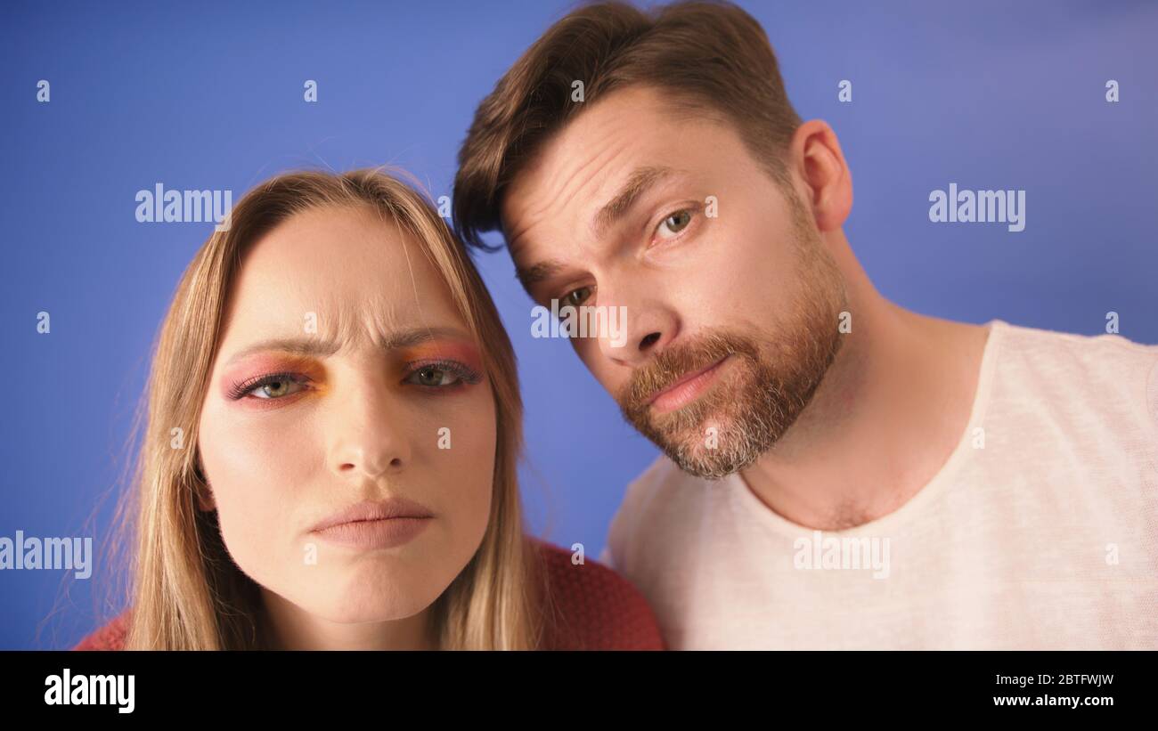 Young couple looking confused into the camera. Isolated on the blue ...