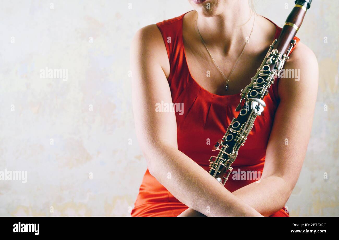 Woman in red dress holds a clarinet Stock Photo - Alamy