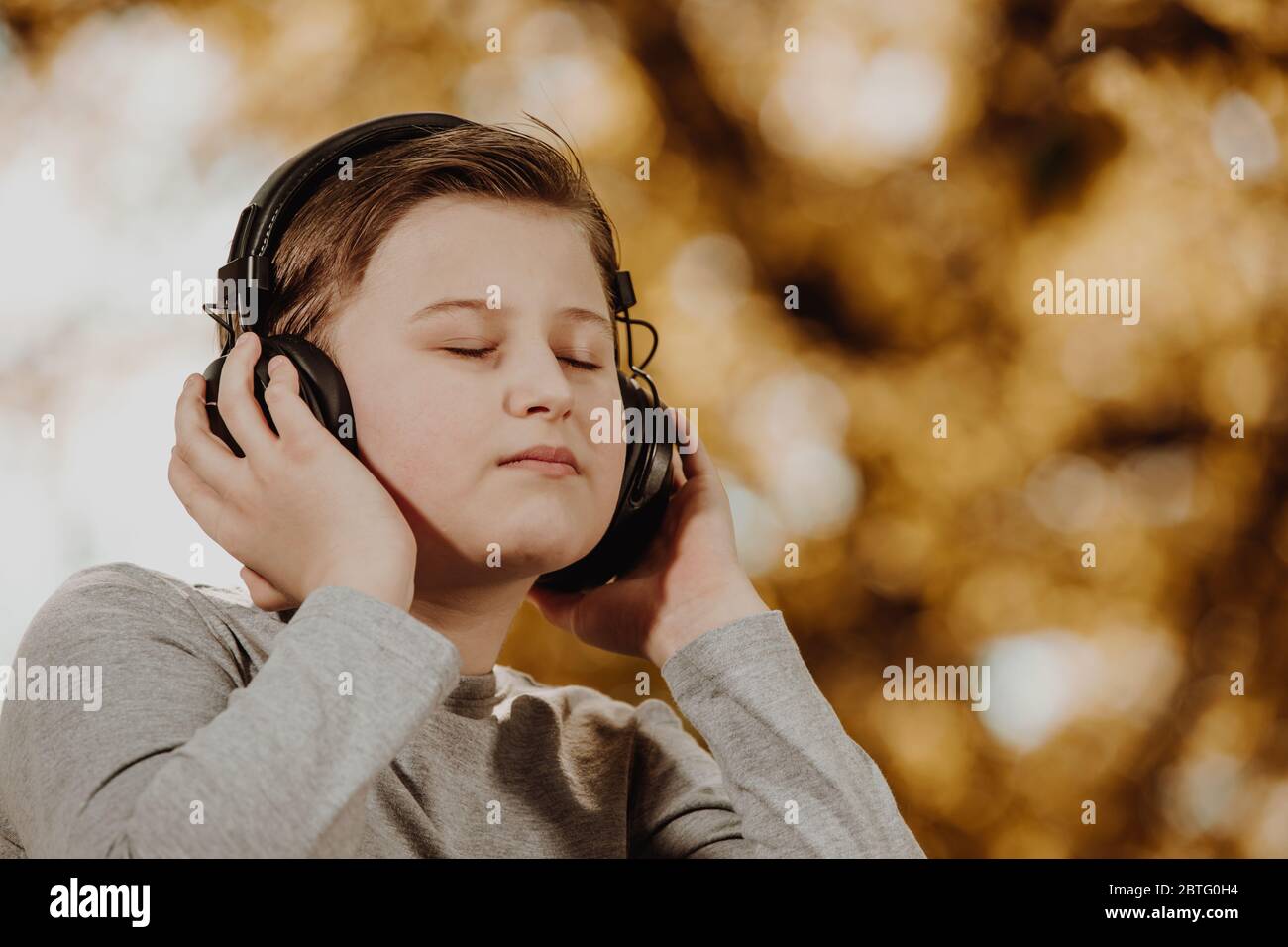 Boy teenager listening soothing music in a forest during lovely sunny ...