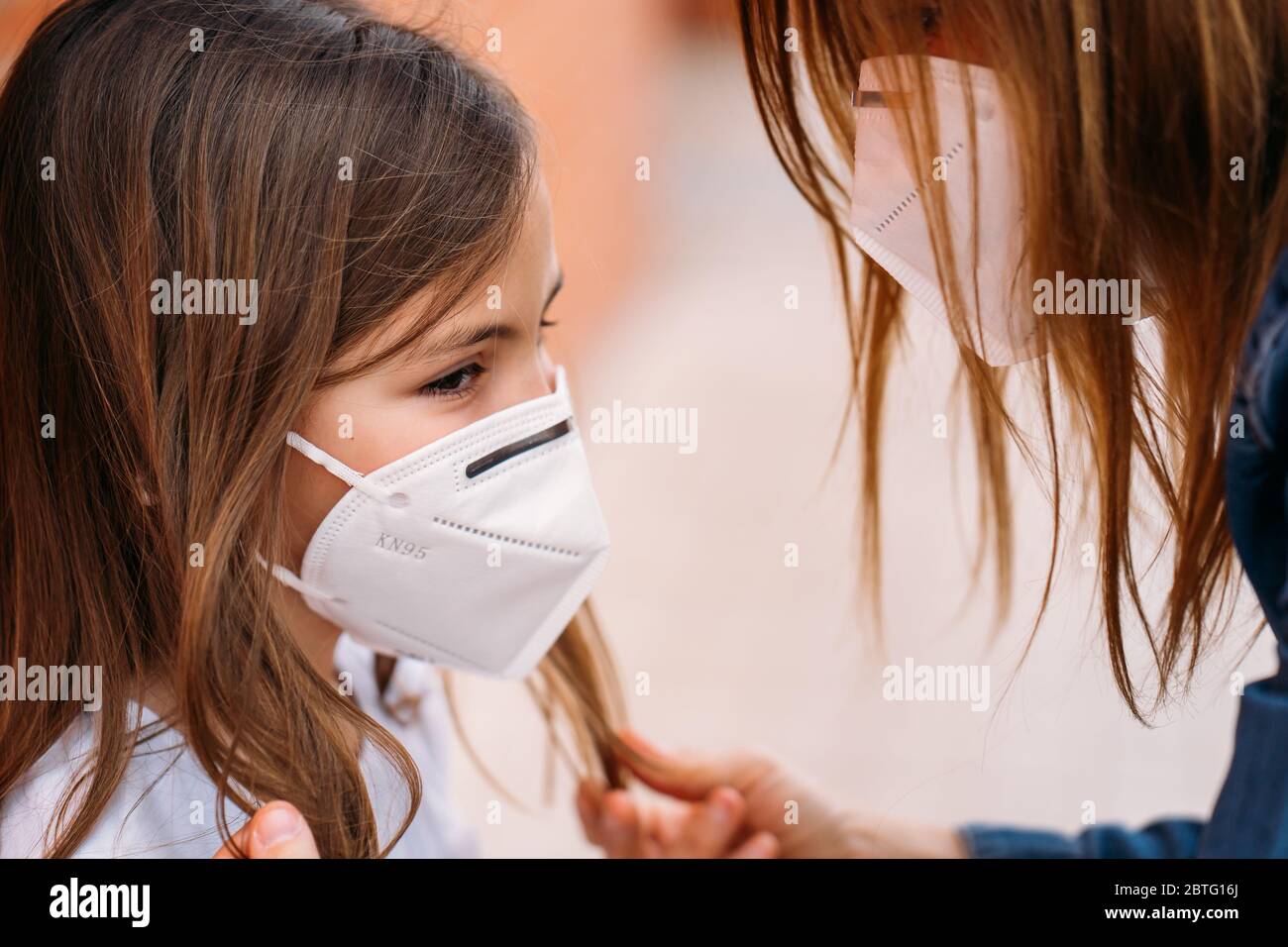 Mother putting face mask on her little daughter on the street Stock ...