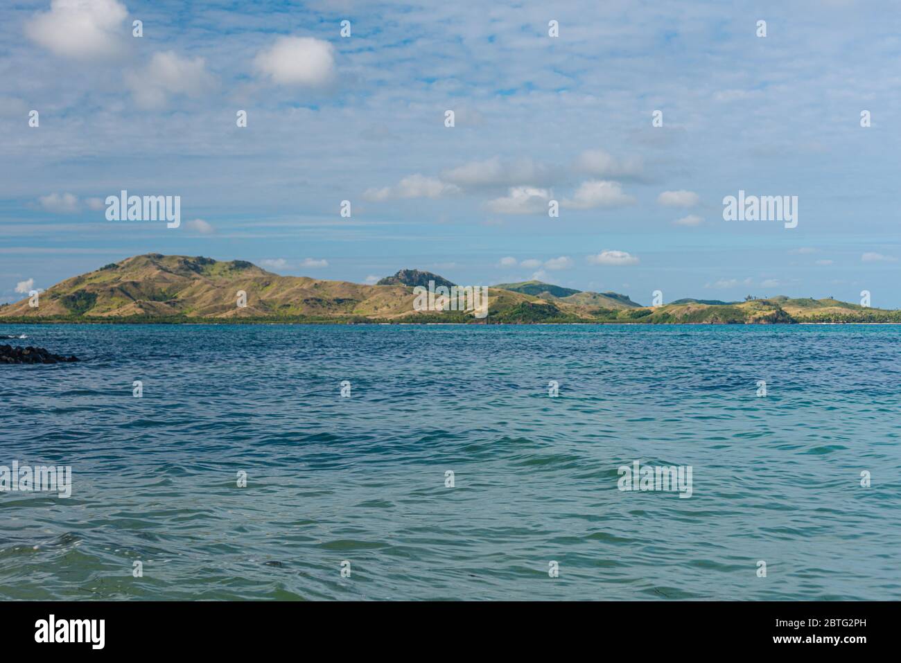 Wide angle view of a hilly tropical island on the horizon blue water ...
