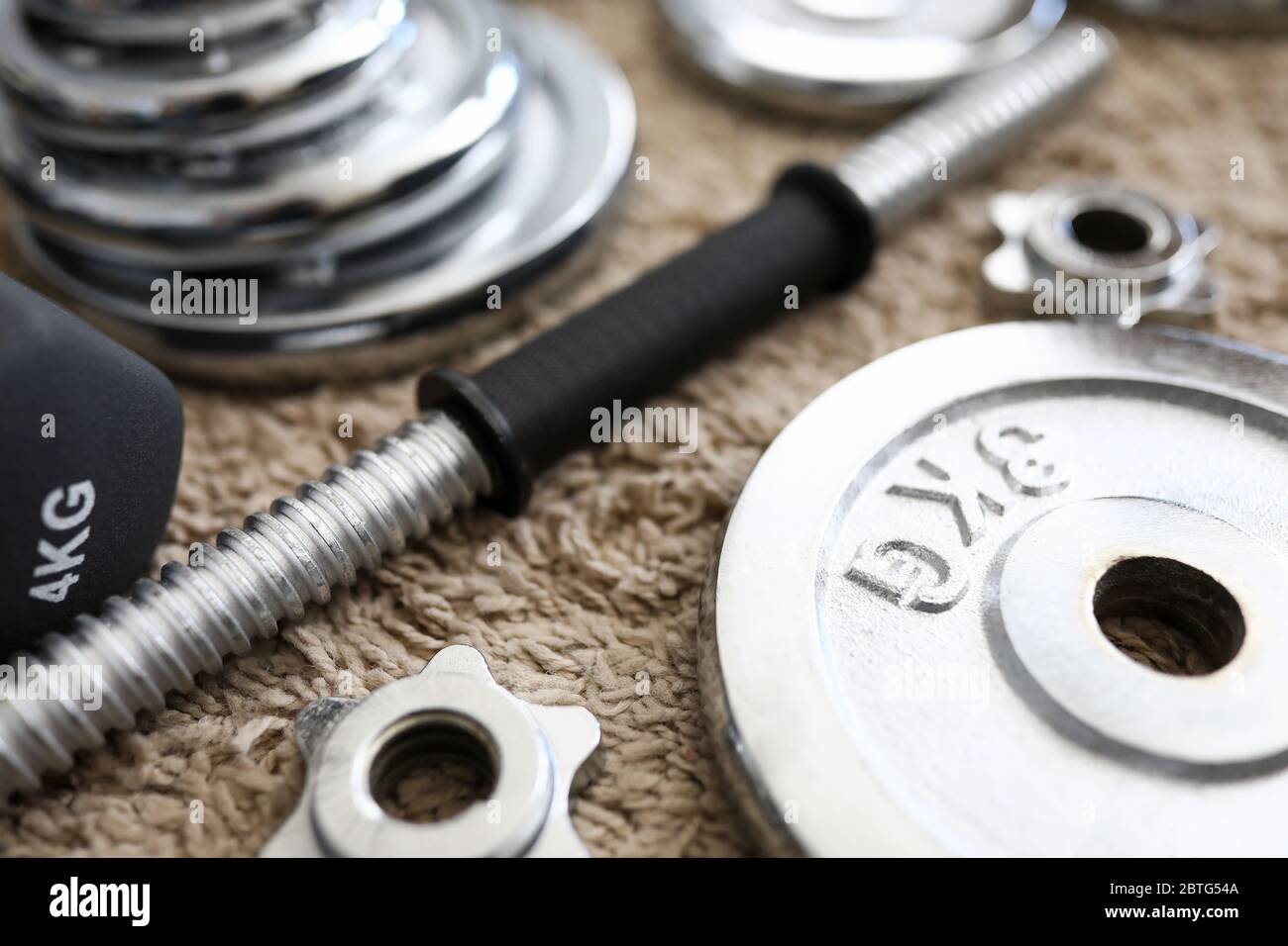 Pile of shiny chrome dumbbells disks lying around grip Stock Photo - Alamy