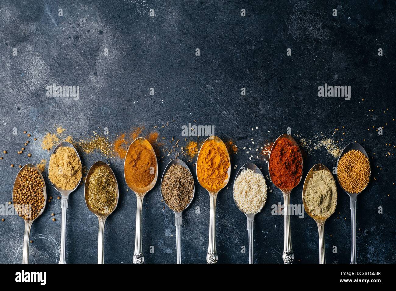 Spices in spoons background. Varieties of spices (turmeric, pepper ...