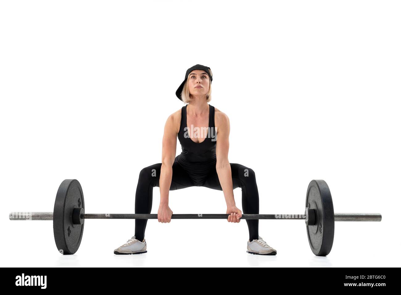 Young woman doing deadlift with a barbell isolated on white. Front view ...