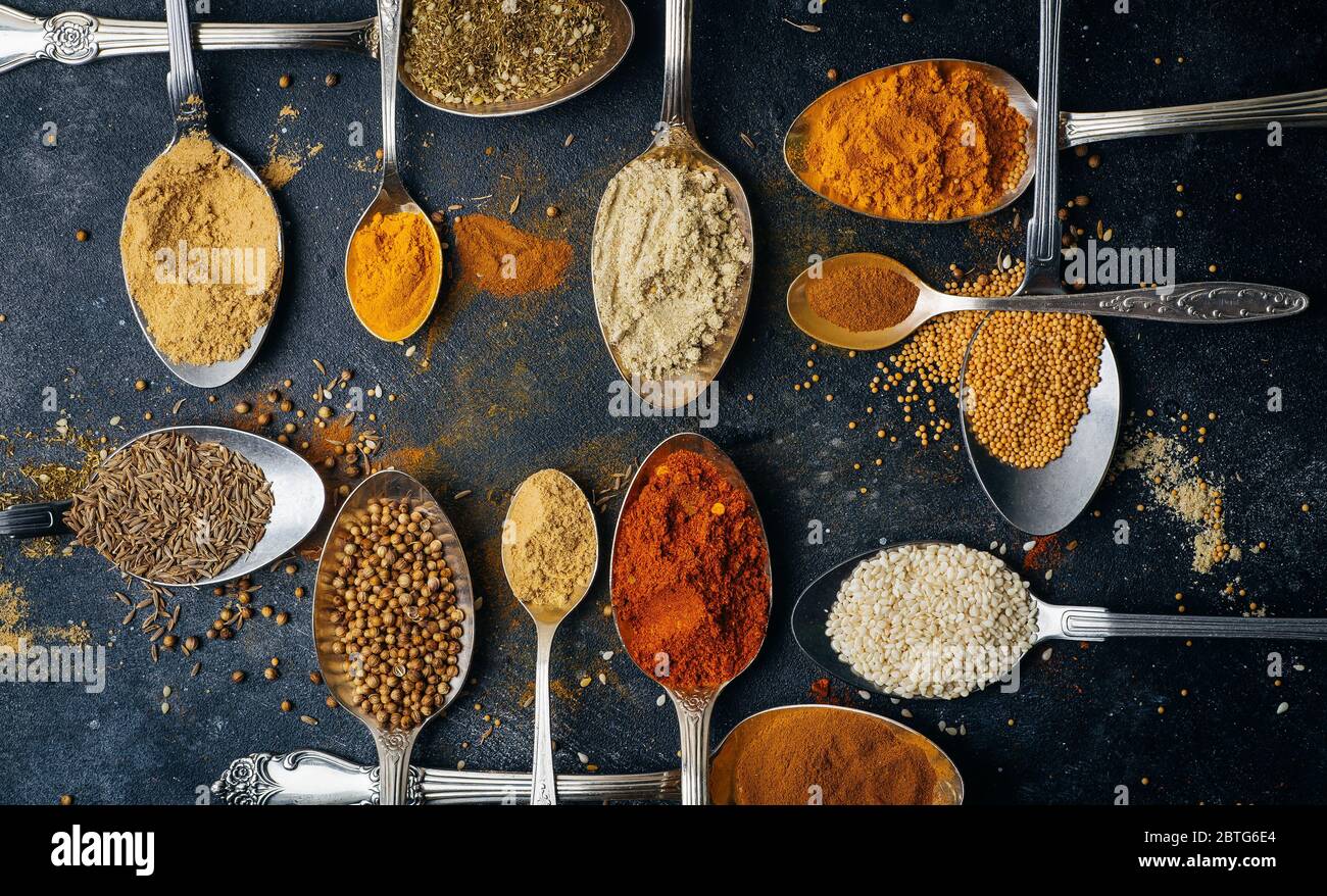 Spices in spoons background. Varieties of spices (turmeric, pepper ...