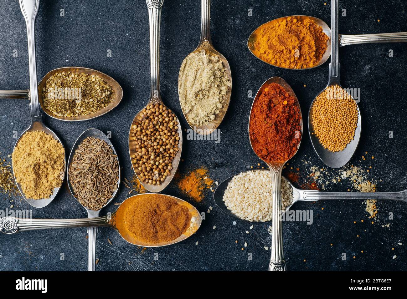 Spices in spoons background. Varieties of spices (turmeric, pepper ...