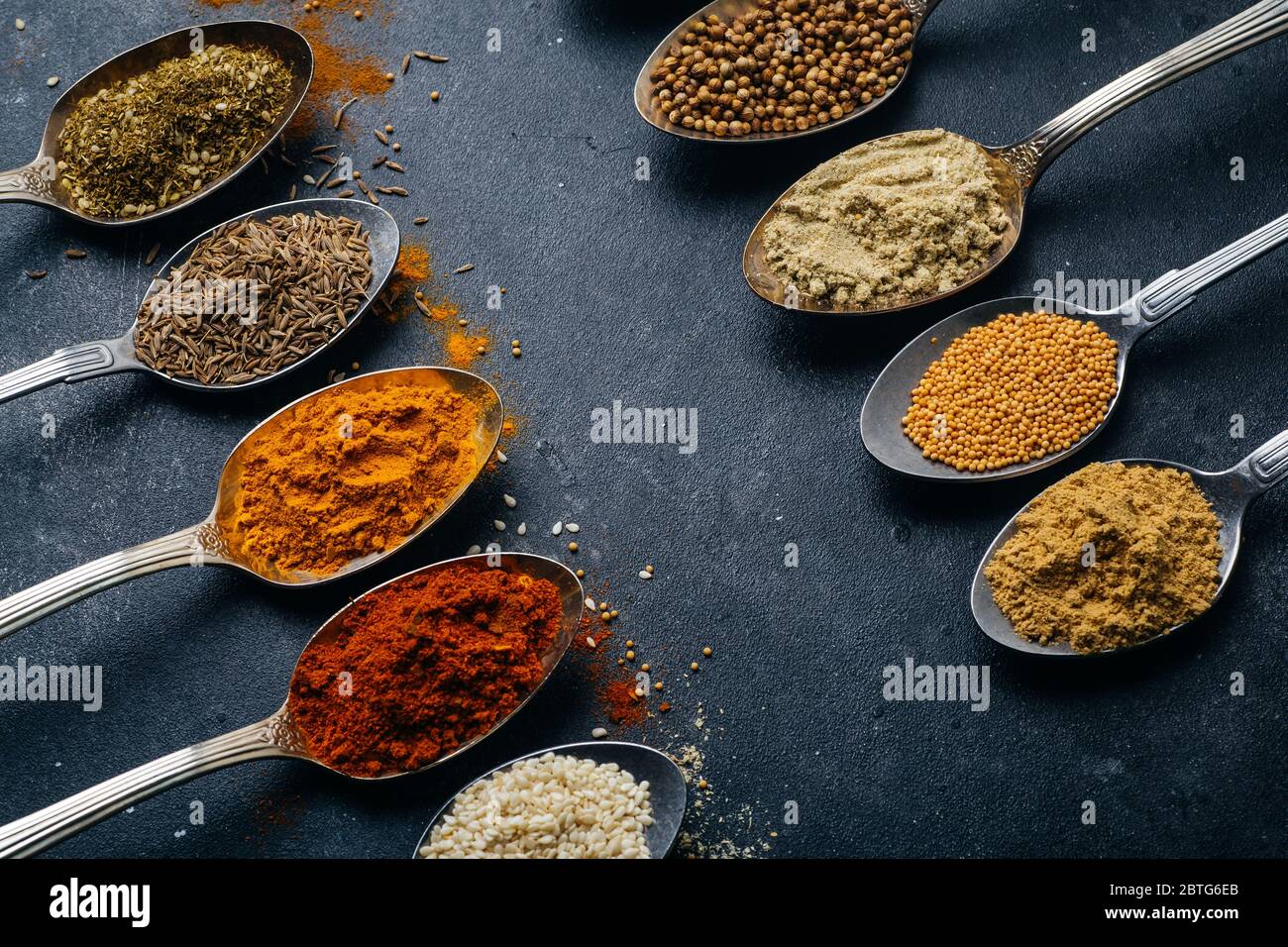 Spices in spoons background. Varieties of spices (turmeric, pepper ...