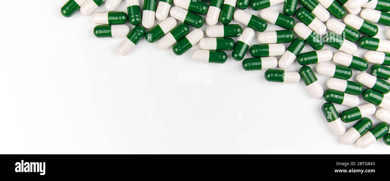 Panoramic green pharmaceutical capsules on a white background ...