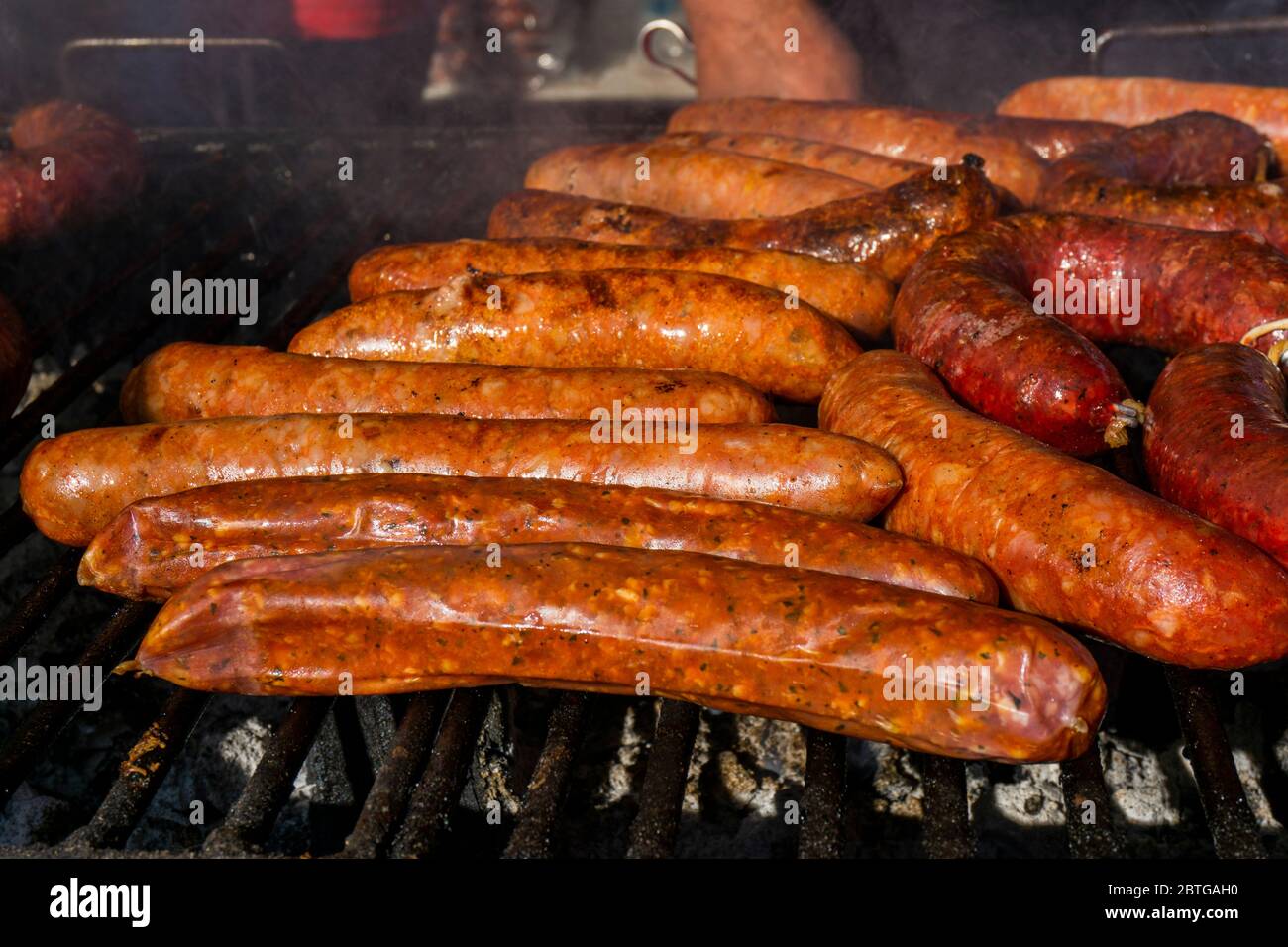 Grilling different kinds of sausages, dry and fresh meat on an open ...