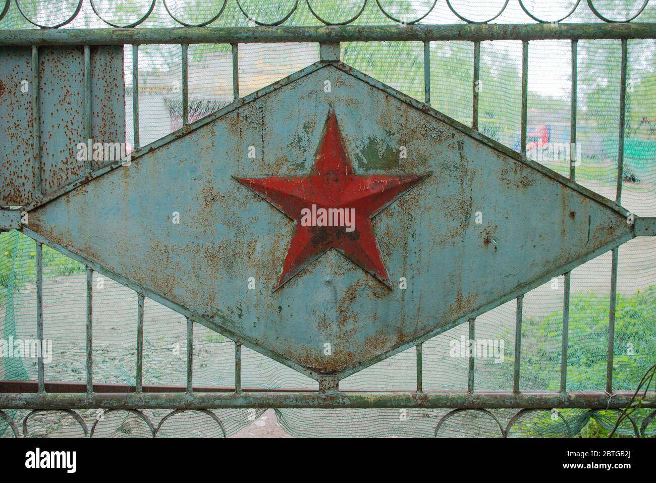 Soviet military five-pointed star on the green scuffed gate. Abandoned ...