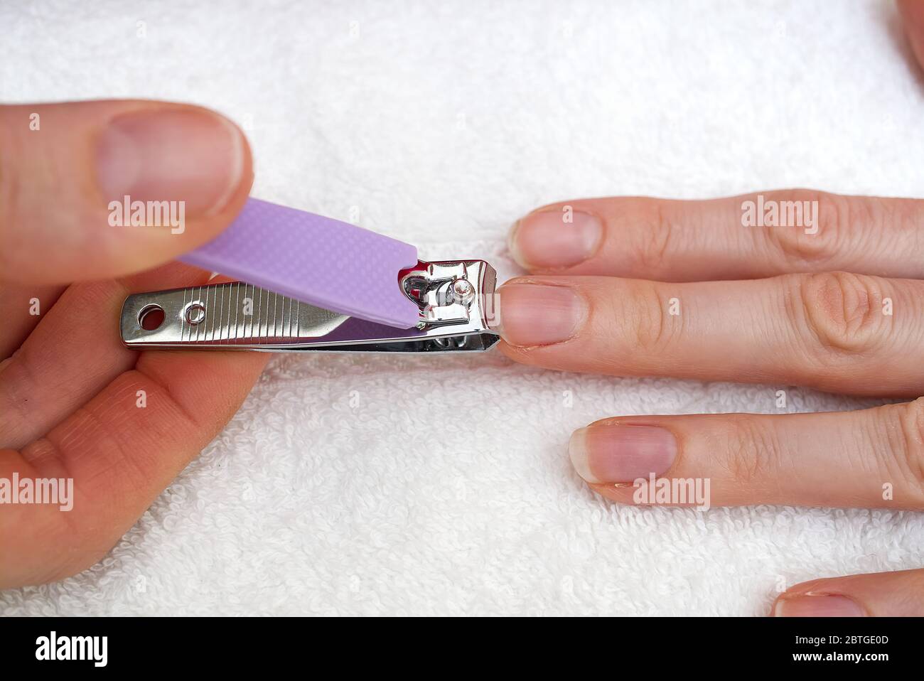 Woman Clipping Nail s with Forceps. Female cuts his nails on a white ...