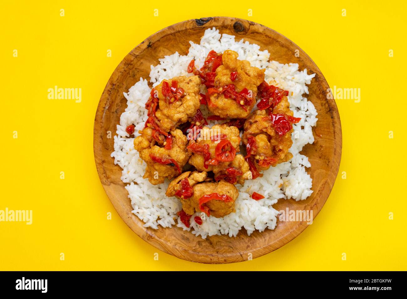 Rice with chicken nuggets sprinkled with chili sauce is served in a ...