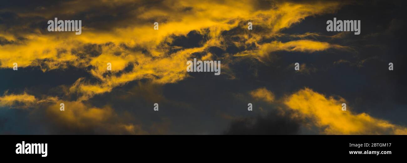 Panorama fluffy thunderstorm clouds illuminated by disappearing rays at ...