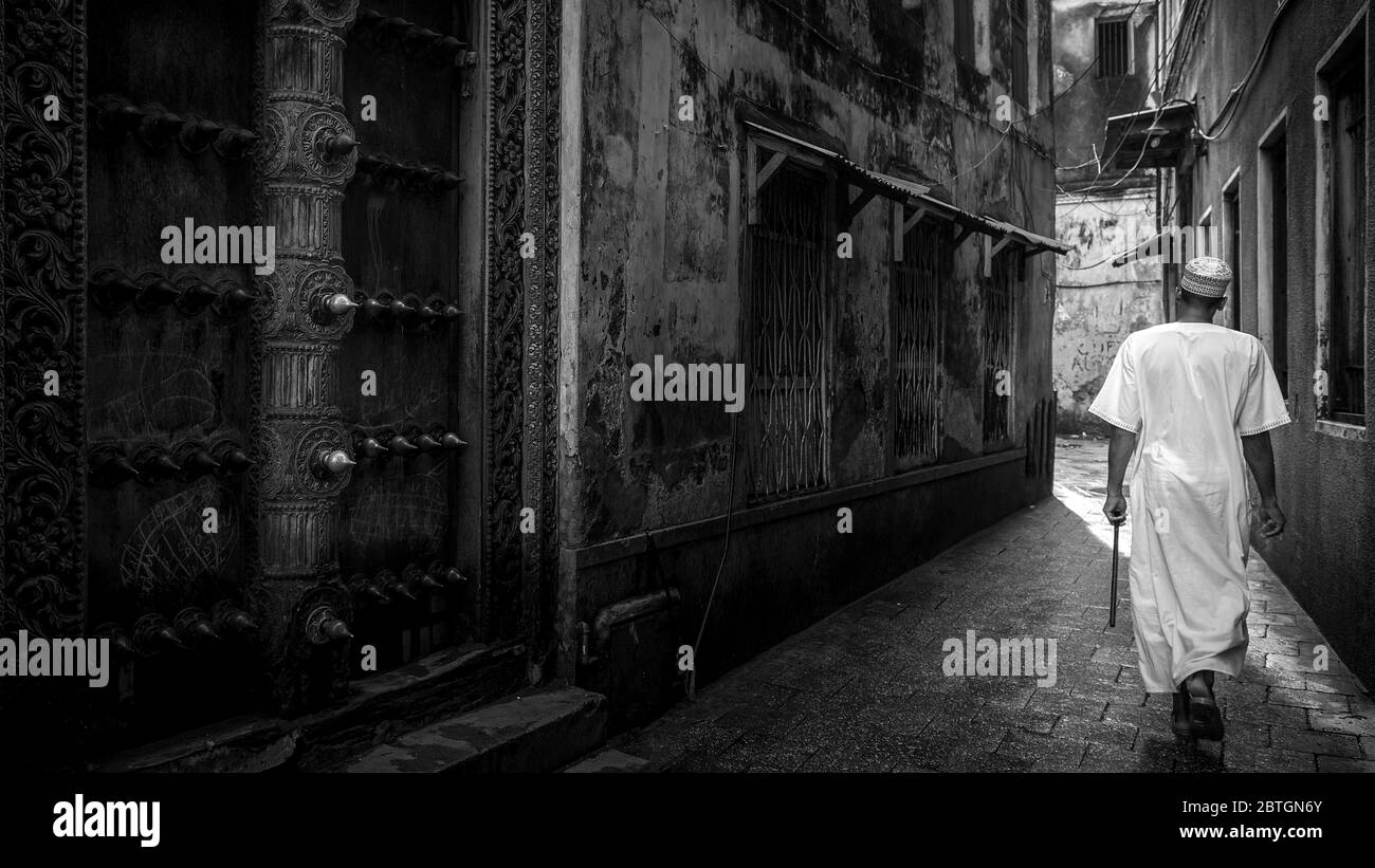islamic man walking through narrow streets of Stonetown Stock Photo - Alamy