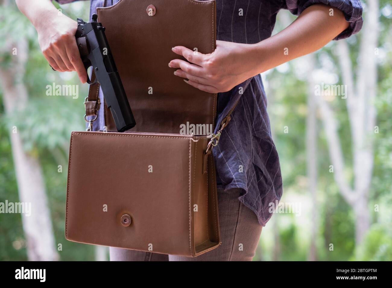 Young Asia woman putting a gun in her handbag, Women hand pulling a ...