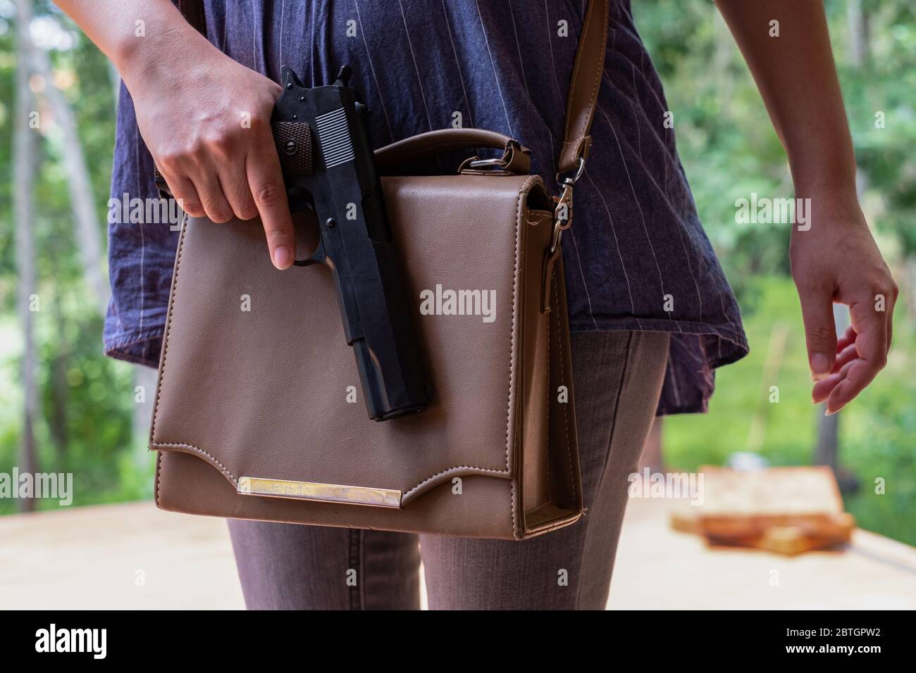 Young Asia woman putting a gun in her handbag, Women hand pulling a ...