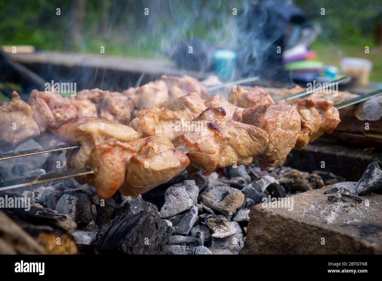 Meat kebabs on metal skewers cooking over the hot coals of a barbecue ...
